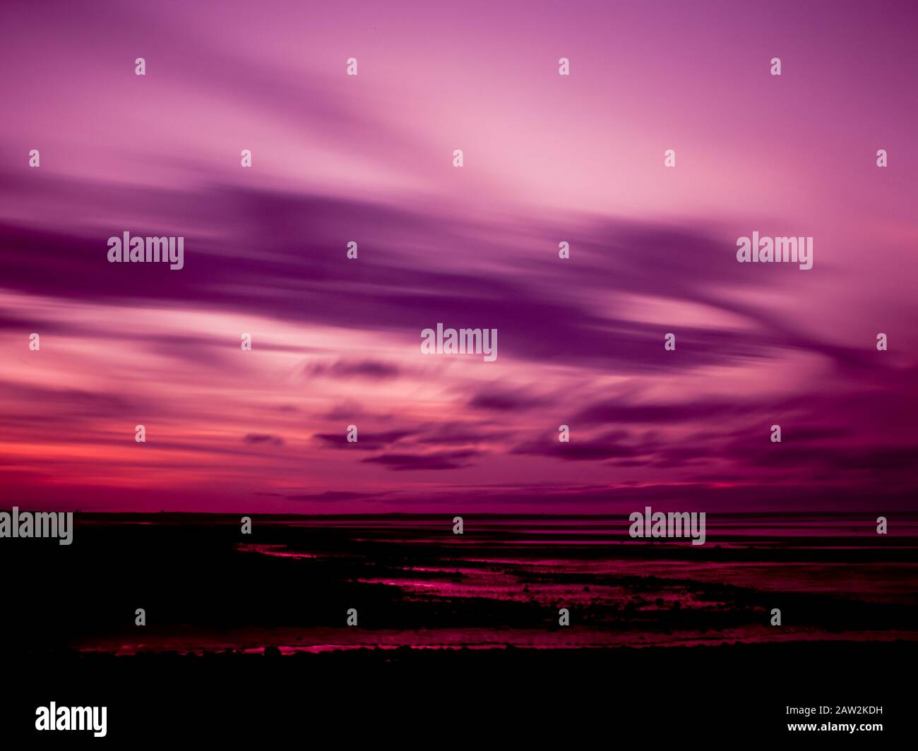 Magenta Tinted Sky Over A Pink Beach In Silhouette Stock Photo - Alamy