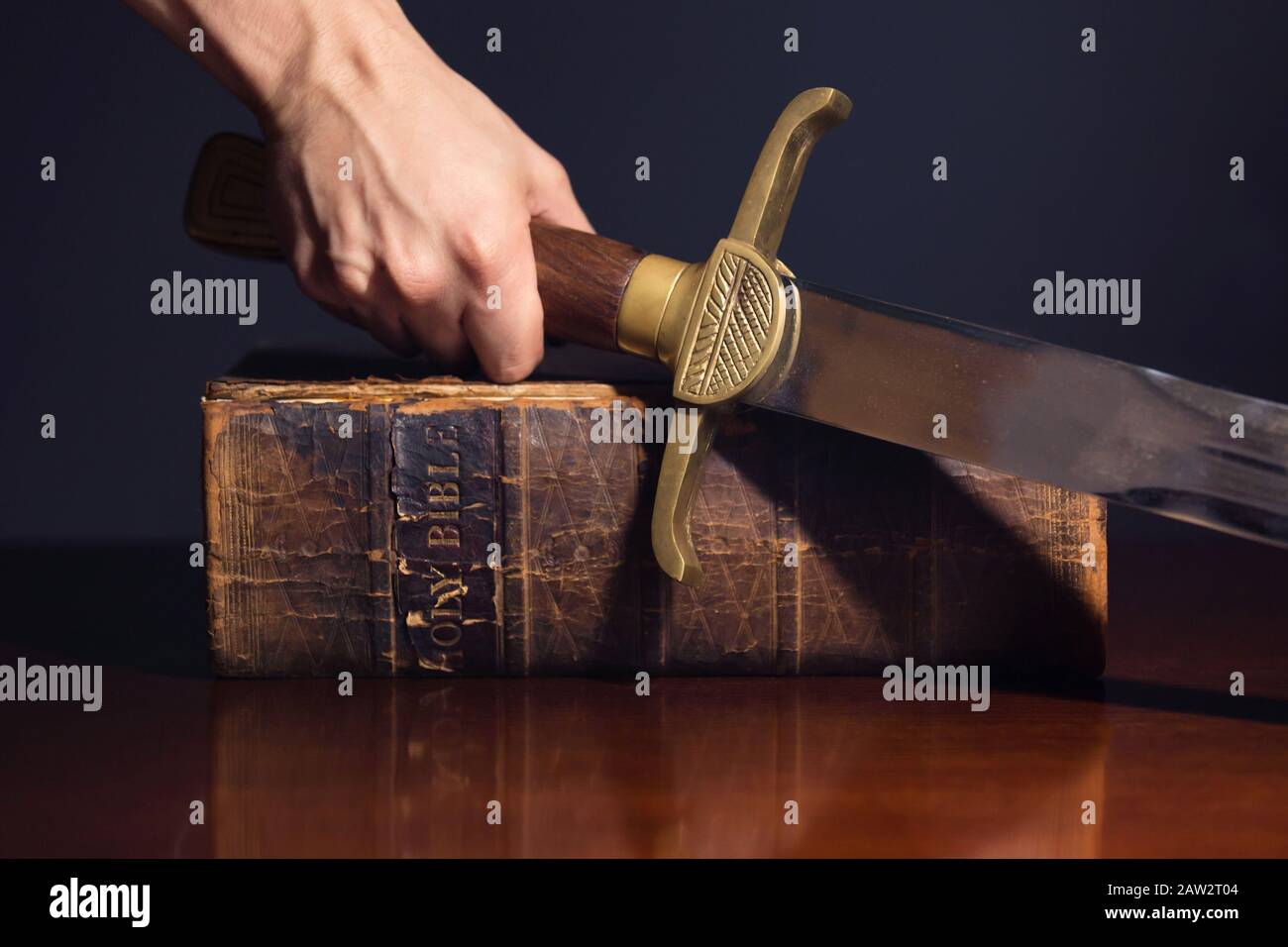 Strong male hand with sword and Bible Stock Photo - Alamy
