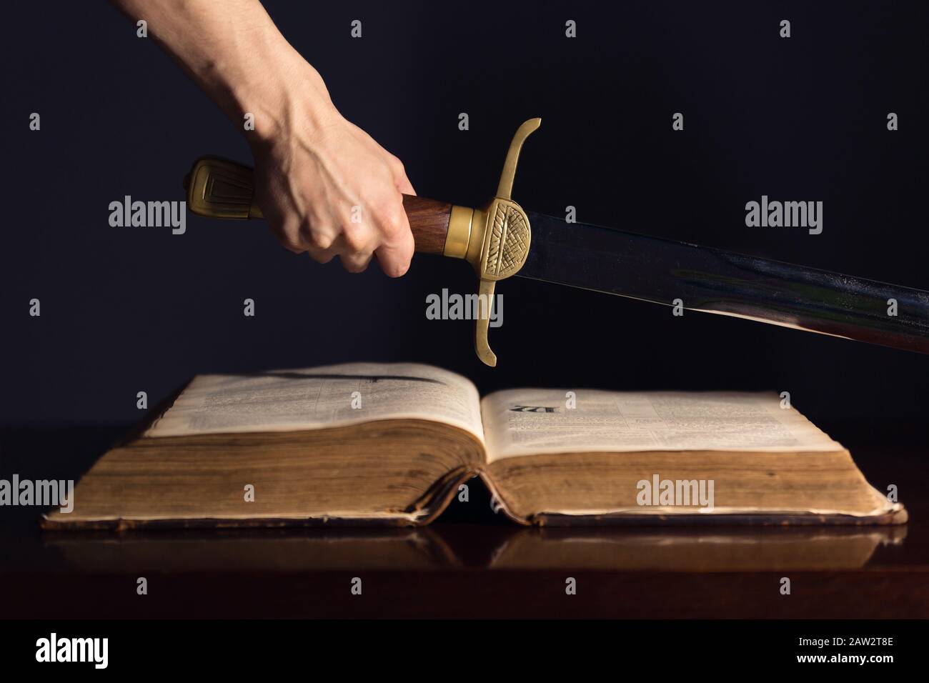 Strong male hand with sword on top of open Bible Stock Photo - Alamy