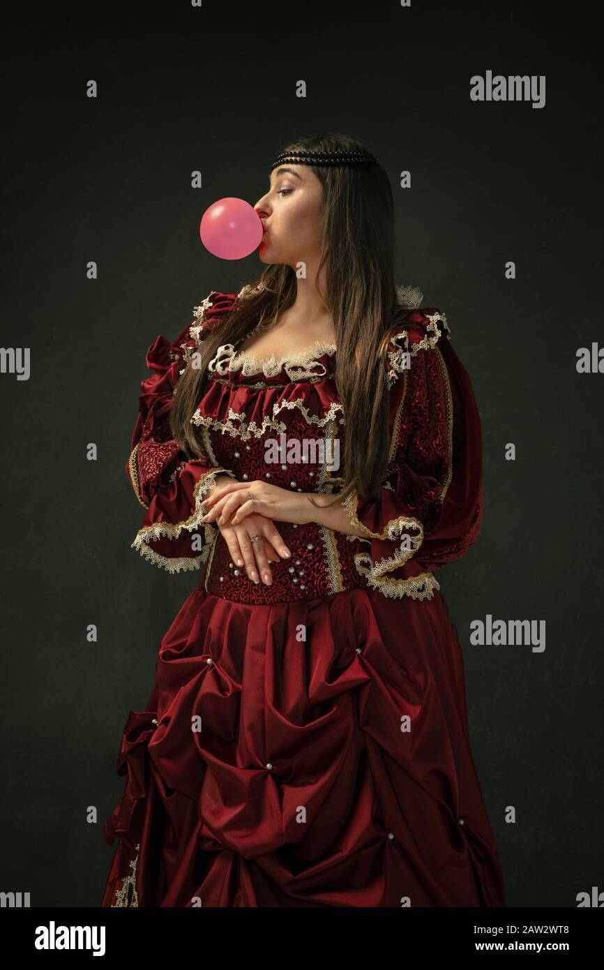 Pink bubble gum. Portrait of medieval young woman in red vintage ...