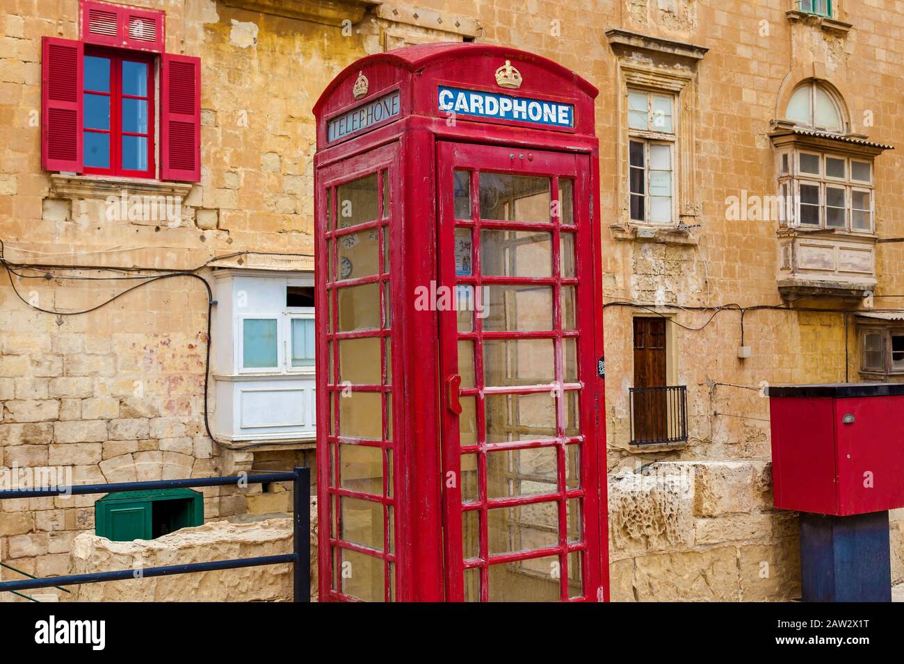 A red telephone box located in front of the facade of a traditional ...