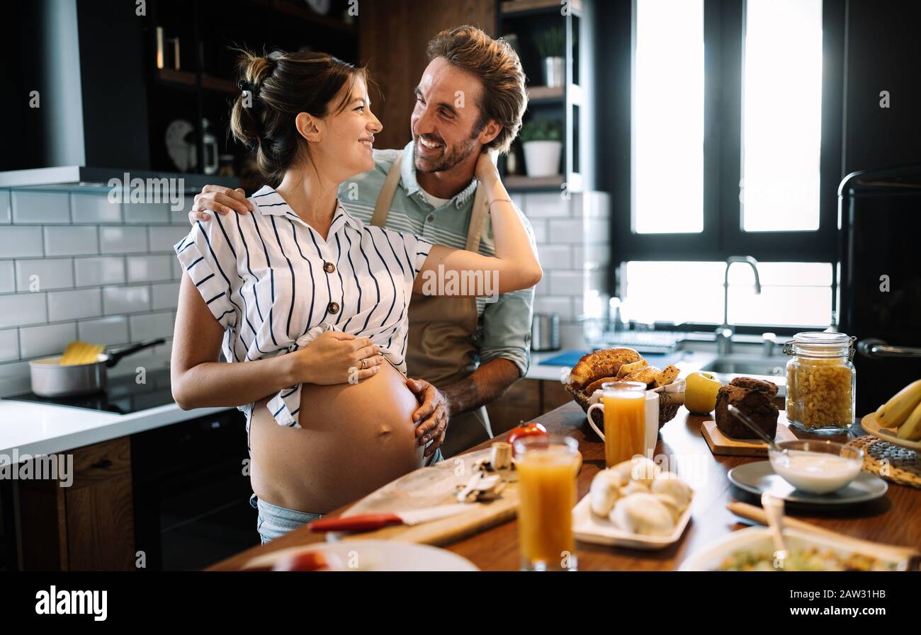 Beautiful young couple is talking and smiling while cooking healthy ...