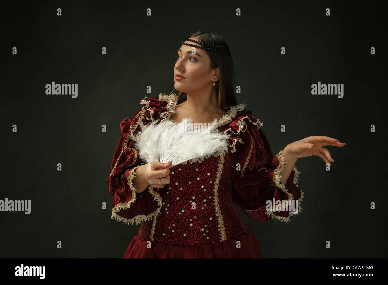 Portrait of medieval young woman in red vintage clothing posing with ...