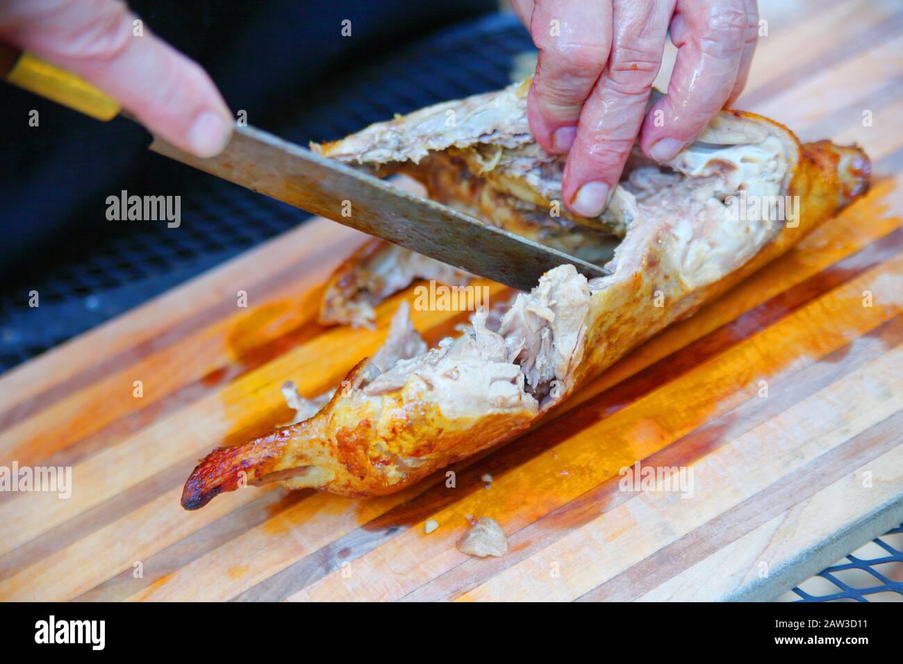 A man cuts up a roast duck on a cutting board outdoors Stock Photo - Alamy