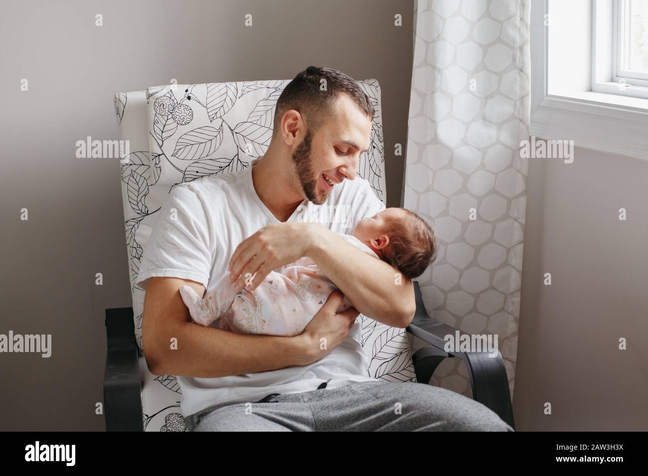 Caucasian father sitting in armchair with newborn baby girl. Parent ...