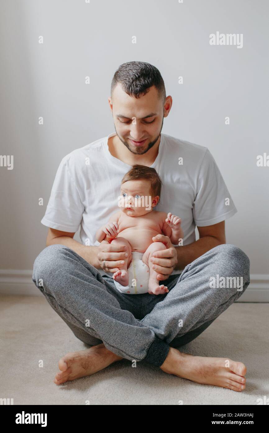 Happy Caucasian father holding newborn baby on laps knees. Man parent ...