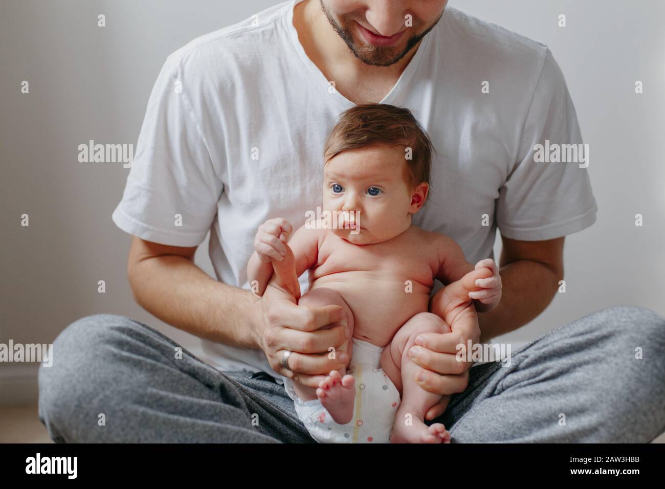 Happy Caucasian father holding newborn baby on laps knees. Man parent ...