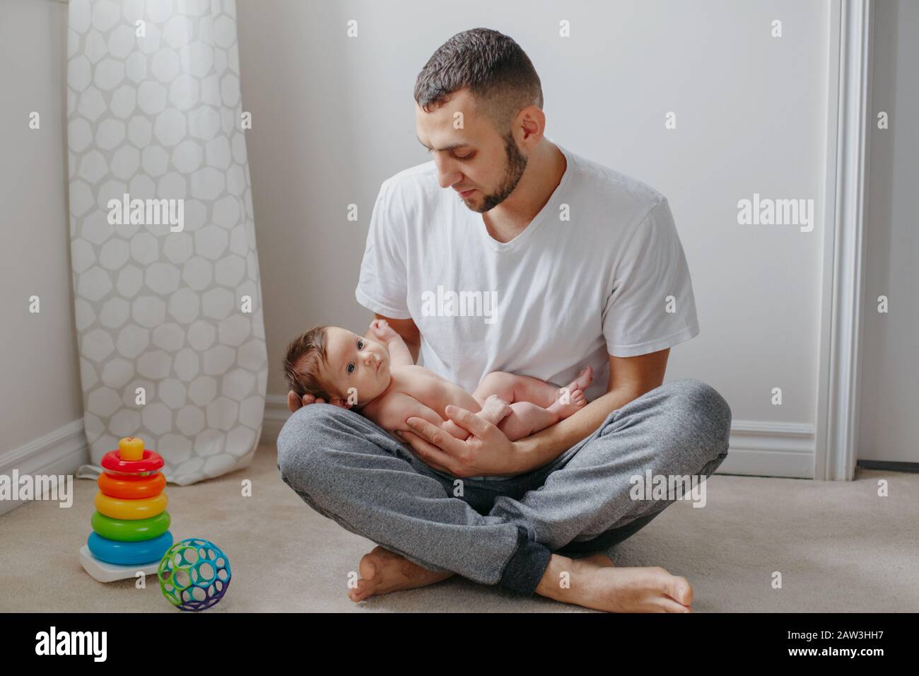 Happy Caucasian father holding newborn baby on laps knees. Man parent ...