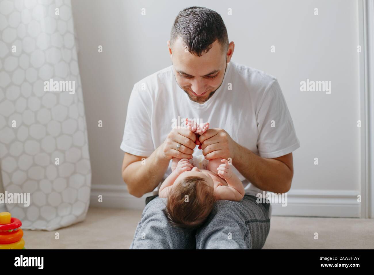 Happy Caucasian father holding newborn baby on laps knees. Man parent ...