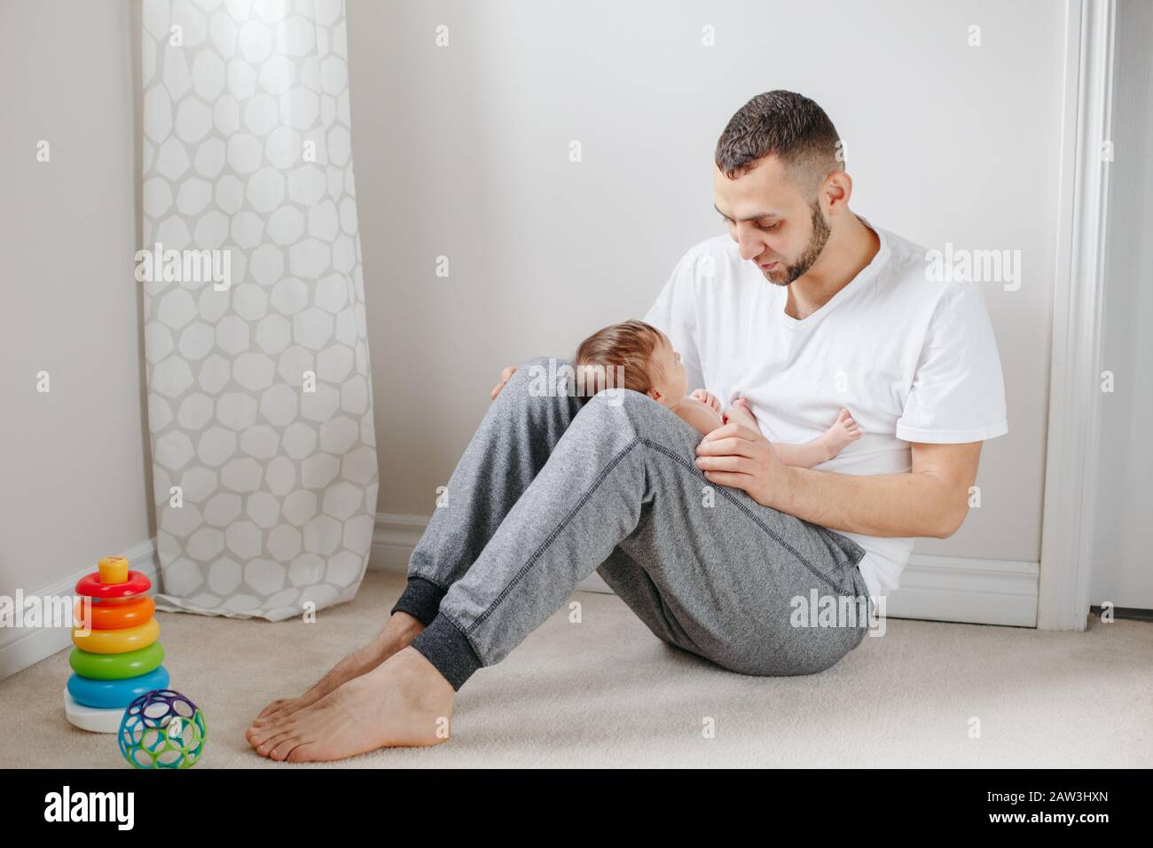 Happy Caucasian father holding newborn baby on laps knees. Man parent ...