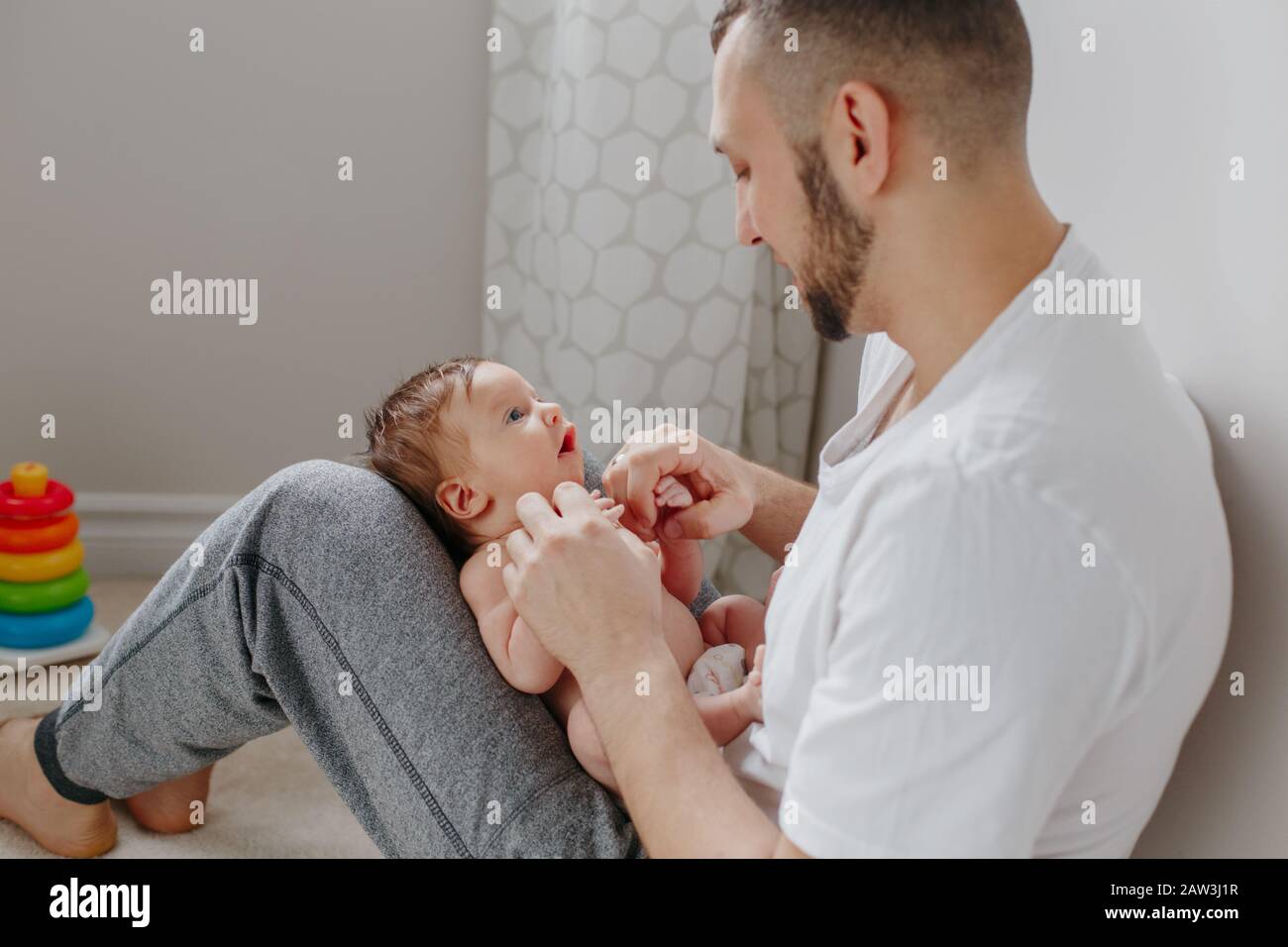 Happy Caucasian father holding newborn baby on laps knees. Man parent ...