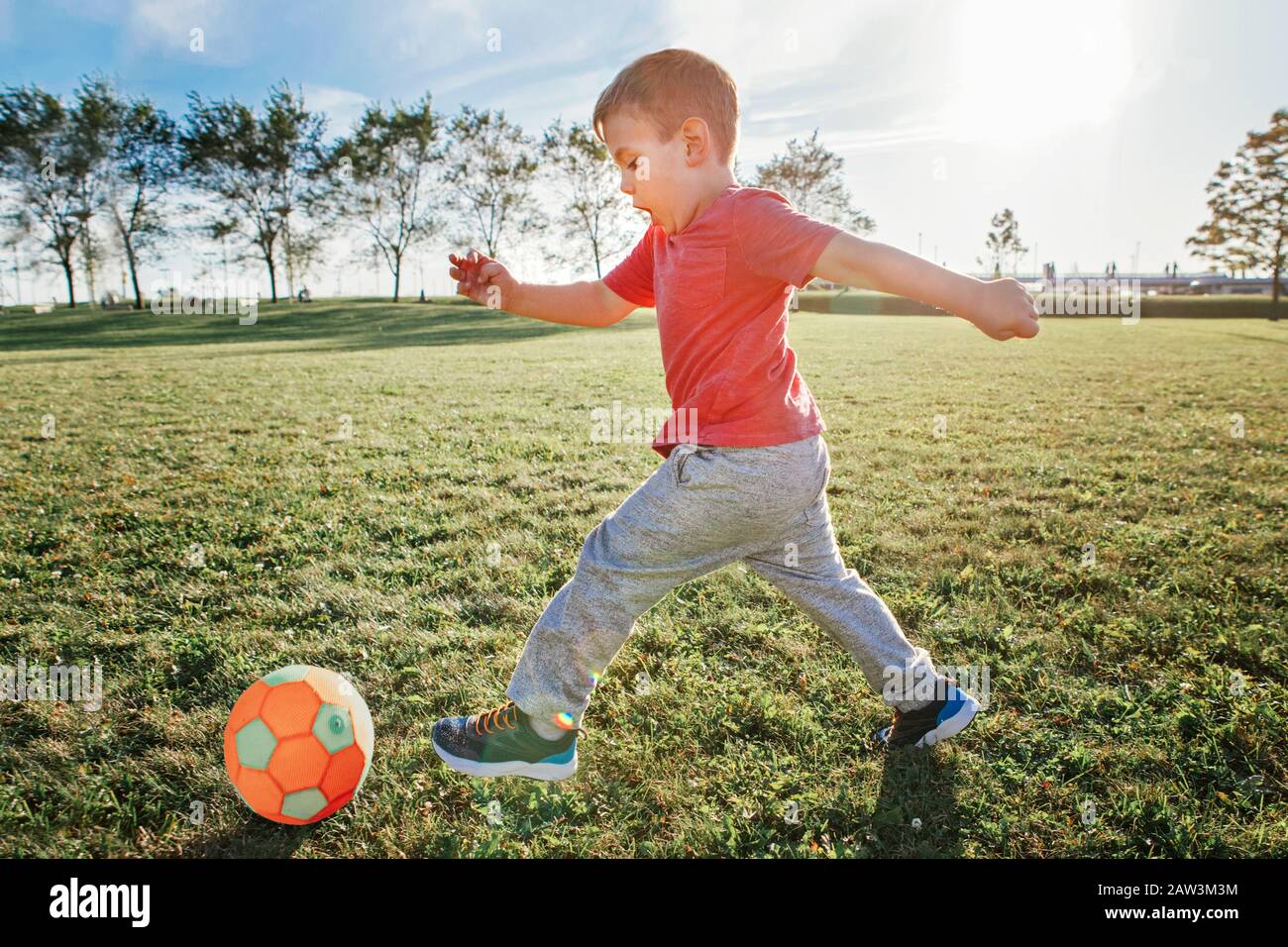Little preschool Caucasian boy playing soccer football on playground ...