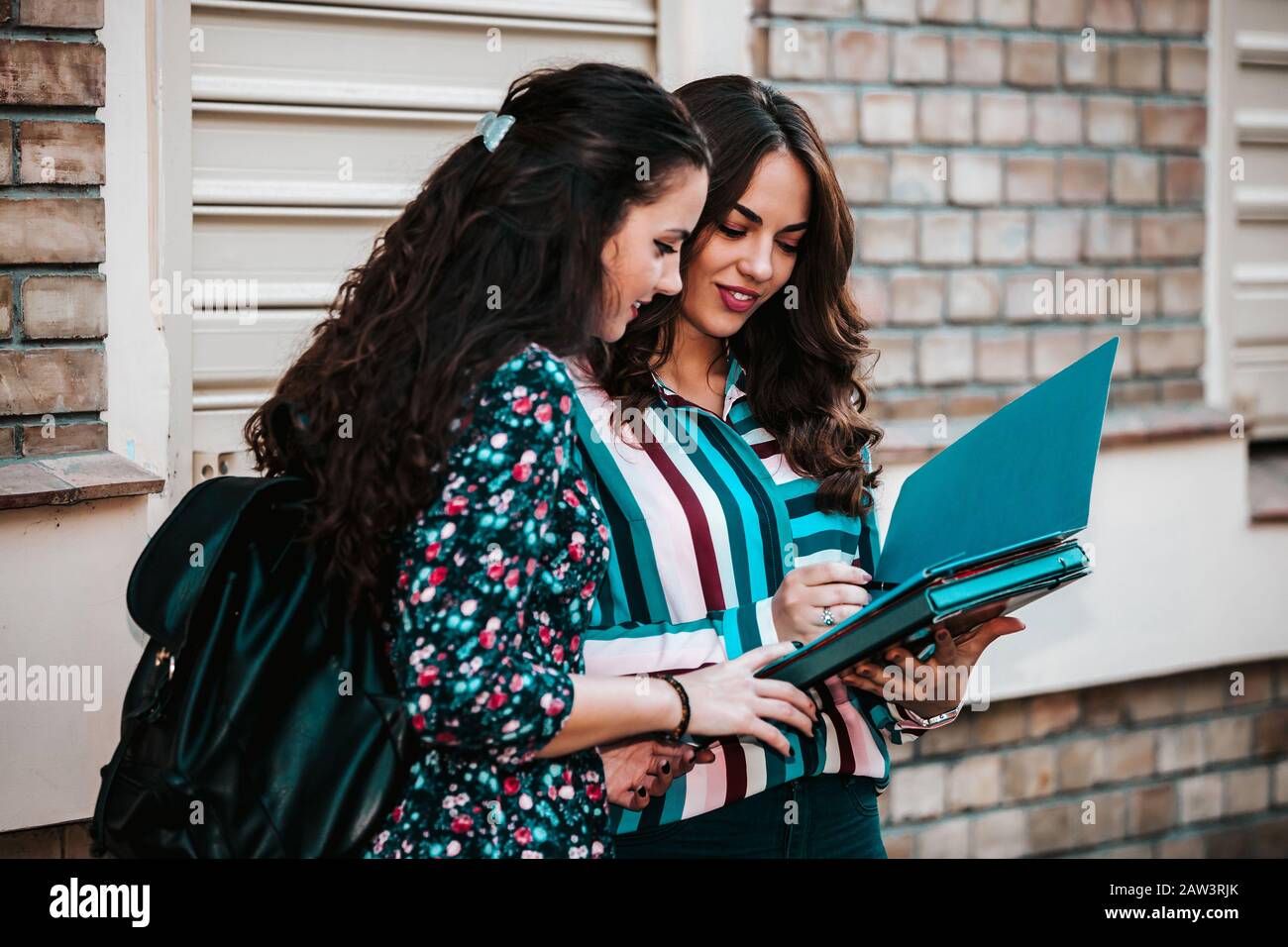 Two beautiful female friends, students checking paper notes before exam ...