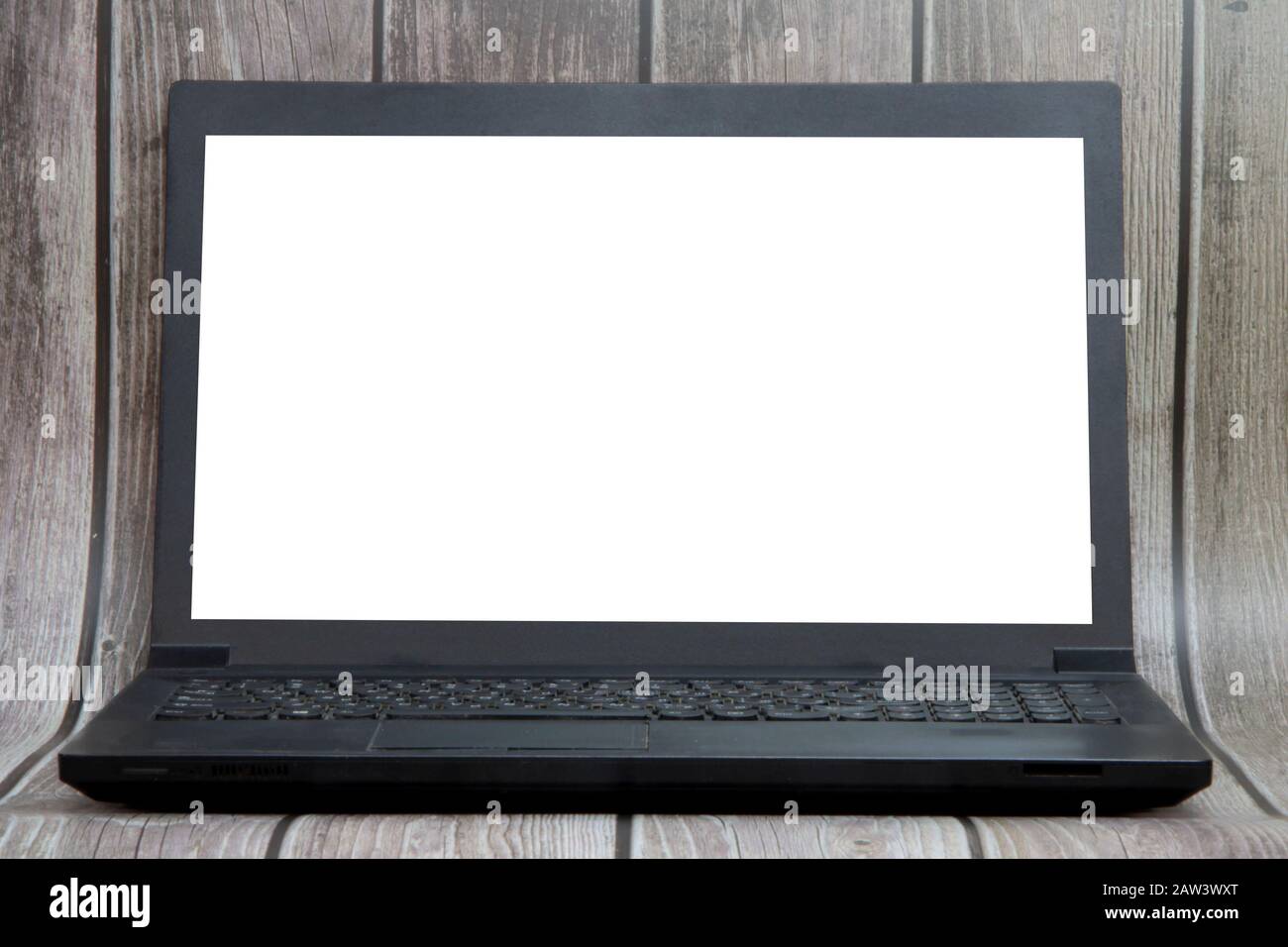 A laptop with a white screen stands on the background of wooden boards ...