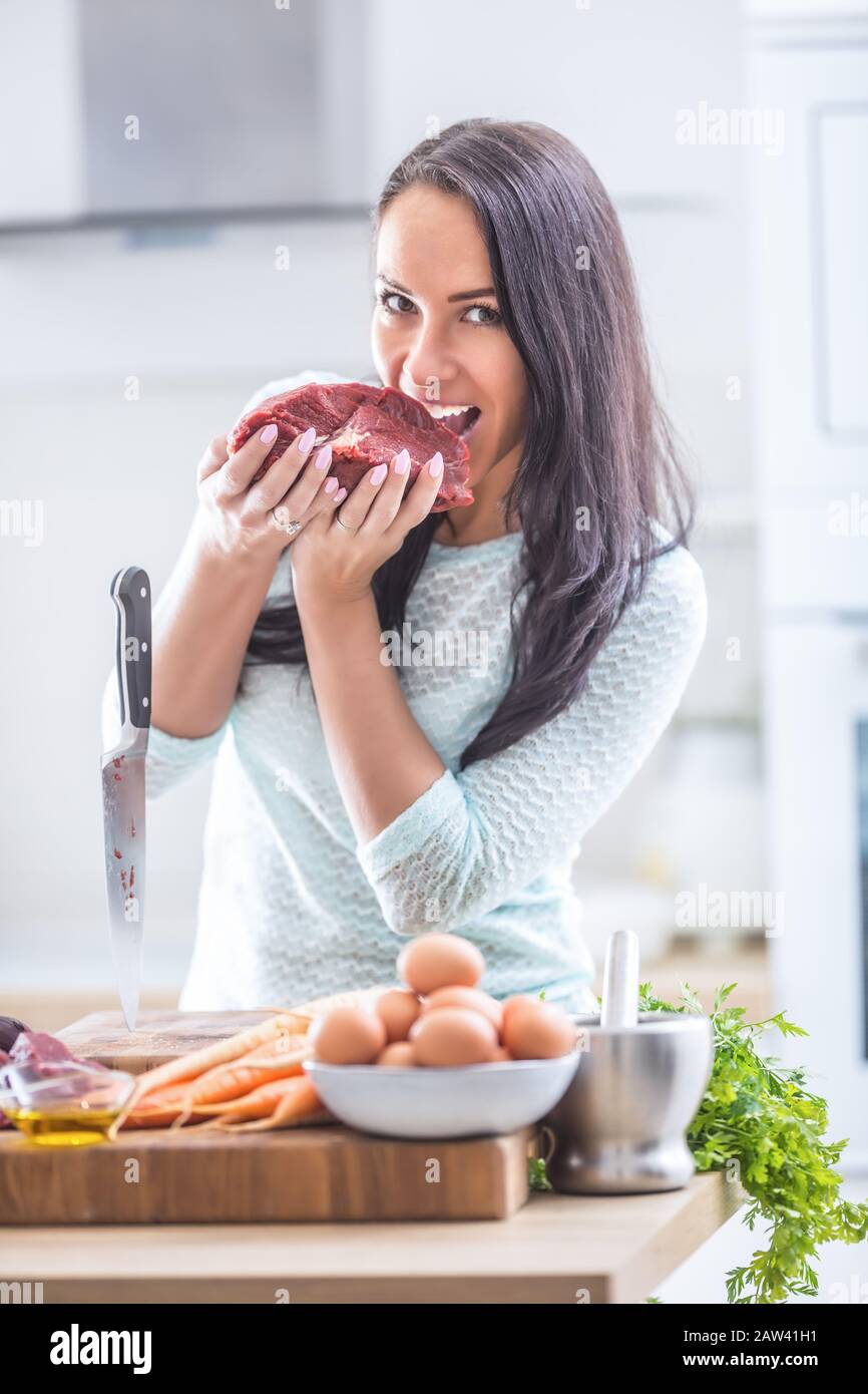 Cheerful female cook in kitchen holding raw beef meat Stock Photo - Alamy