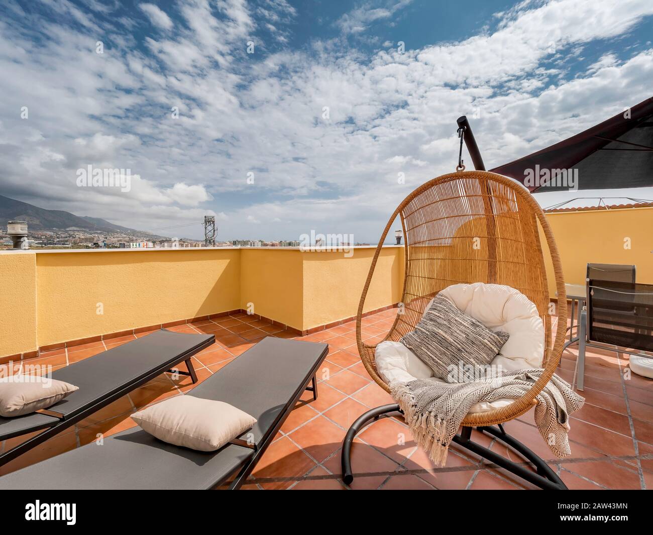 Hanging chair and sun beds in a sunny terrace of a relaxing summer ...