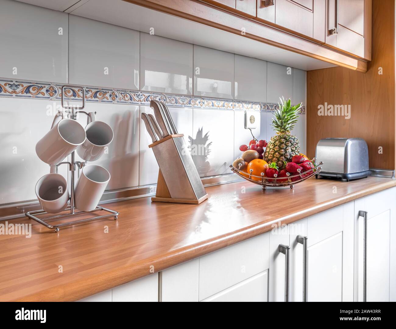 Detail of fruit and kitchenware in a stylish bright kitchen with wooden ...