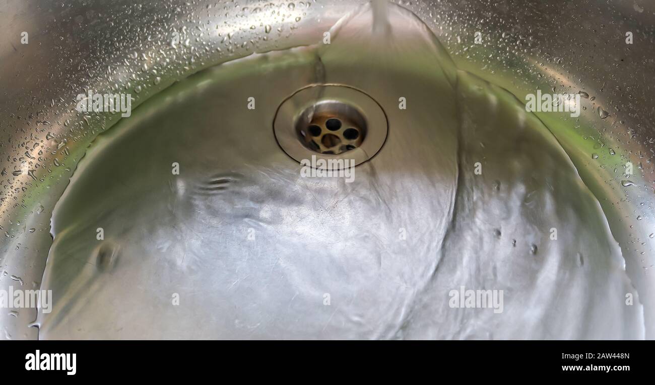 Running water out of a water tap in a metallic kitchen sink Stock Photo ...
