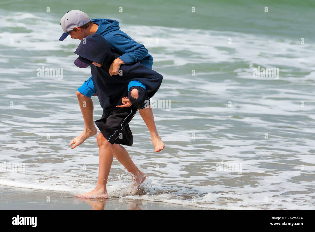 Two brothers playing piggyback at water's edge in Lincoln City on the ...