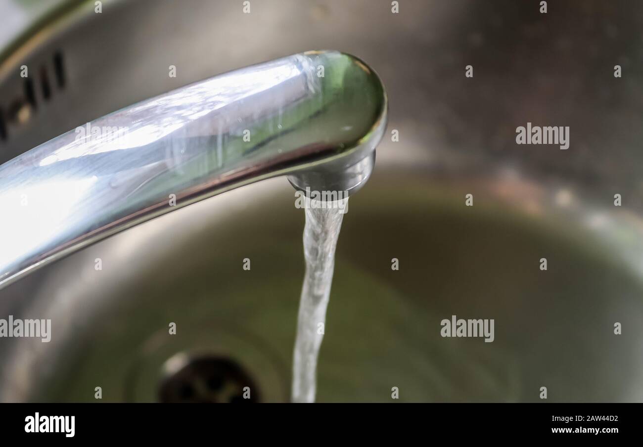 Running water out of a water tap in a metallic kitchen sink Stock Photo ...