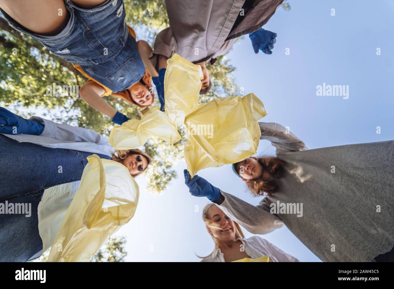 Group of activists friends throw a lot of garbage in a bag. Bottom-up ...