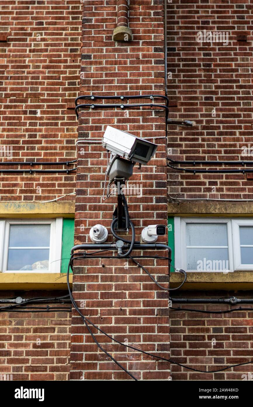 a CCTV camera on the side of a brick building Stock Photo - Alamy