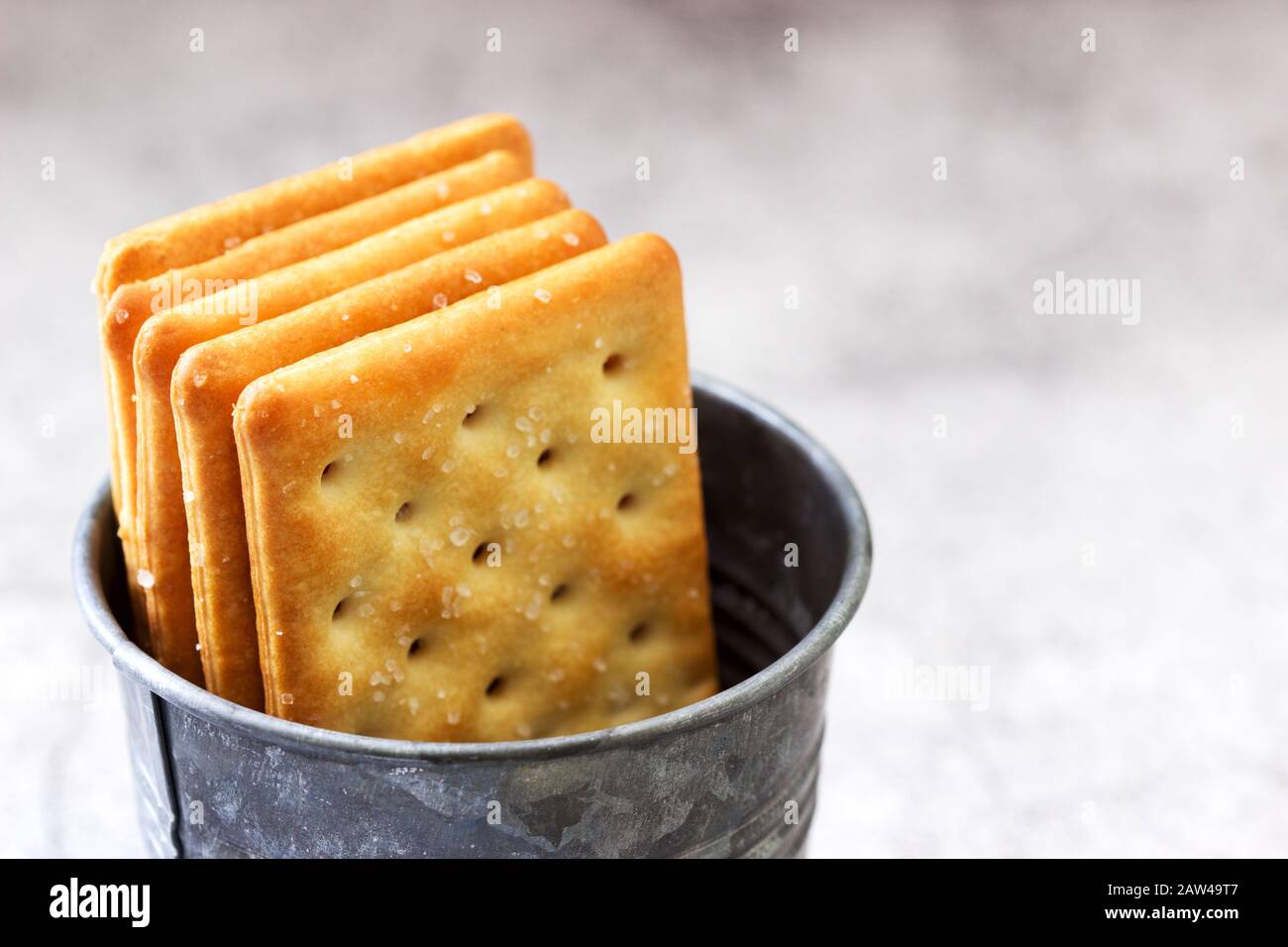 Salty rectangular crackers in a galvanized bucket on a gray background ...