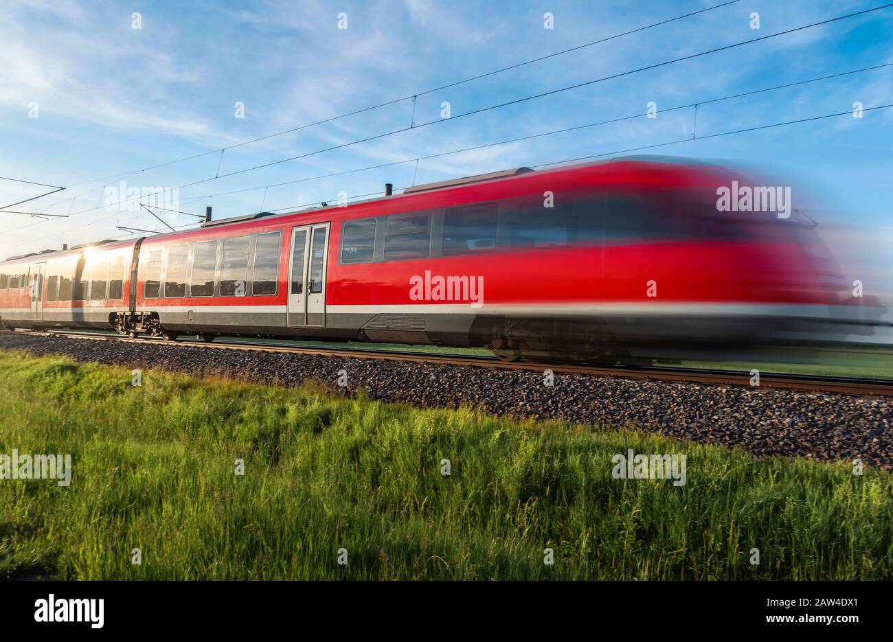 Modern red train, in motion blur, traveling through green nature ...