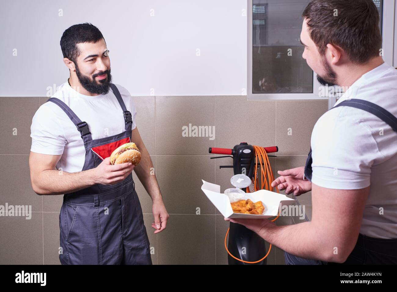Worker wearing uniform eating burger during a lunch break Stock Photo ...