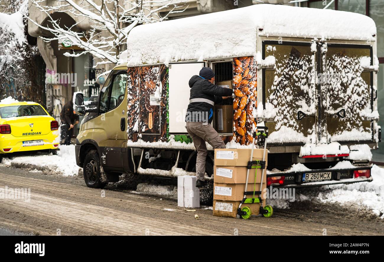 Man, male in winter coat loading a pick up truck on the road in the ...