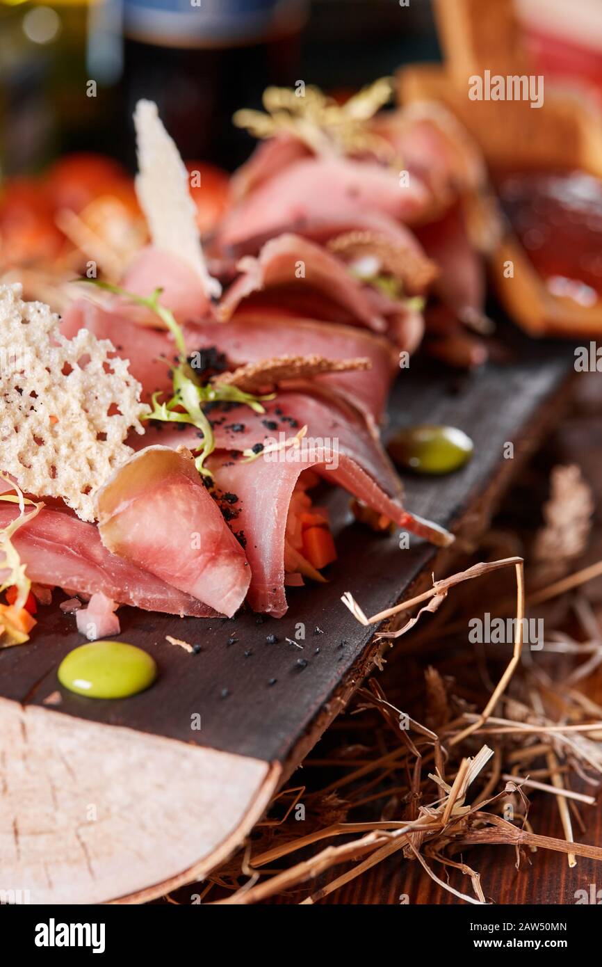 Antipasto on wooden plate close up. Cold smoked meat plate with tomato ...
