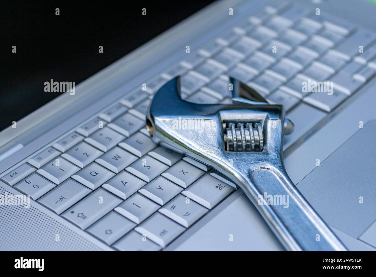 Adjustable wrench on a silver laptop. Computer service, maintenance ...