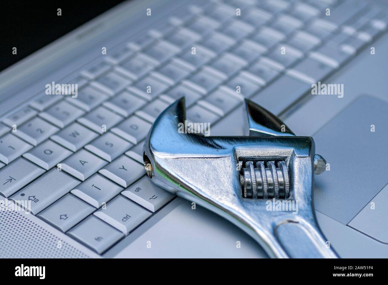 Adjustable wrench on a silver laptop. Computer service, maintenance ...
