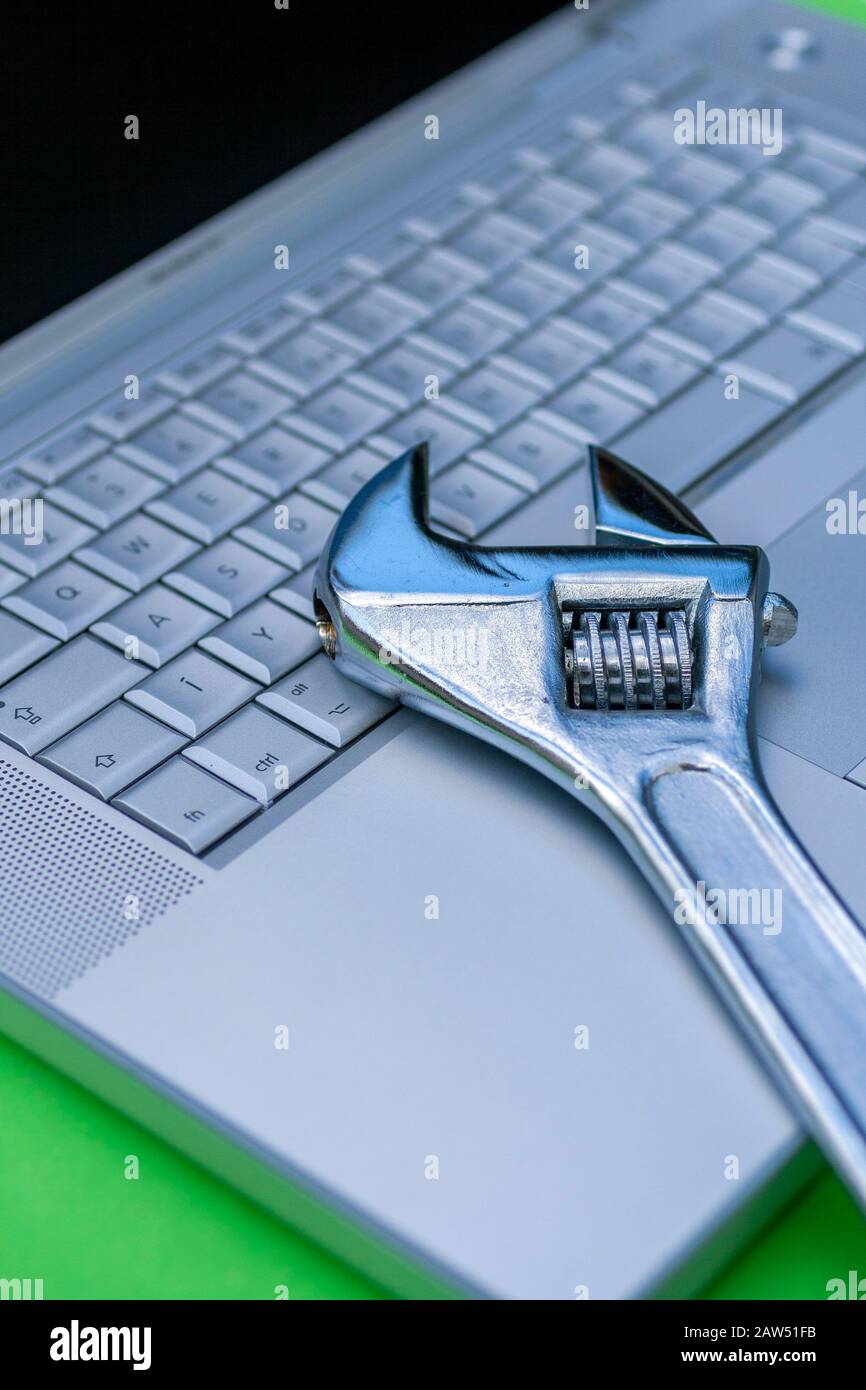 Adjustable wrench on a silver laptop. Computer service, maintenance ...