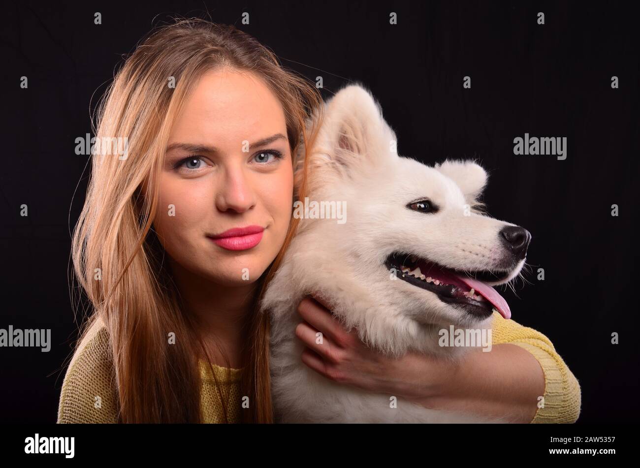 Portrait of beautiful blonde girl and young Samoyed dog with snow-white ...