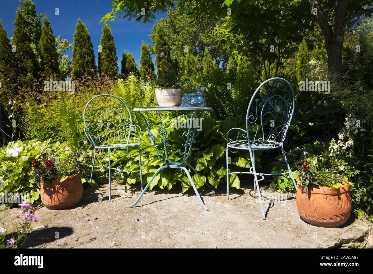 Compacted stone patio with blue wrought-iron bistro table, chairs ...
