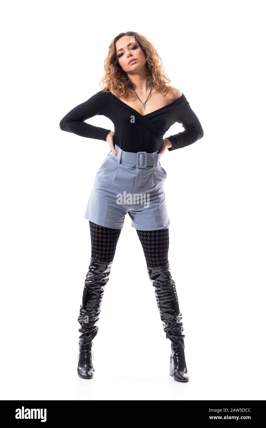 Fashionable young curly hair woman with attitude in akimbo pose wearing elegant modern clothes ...