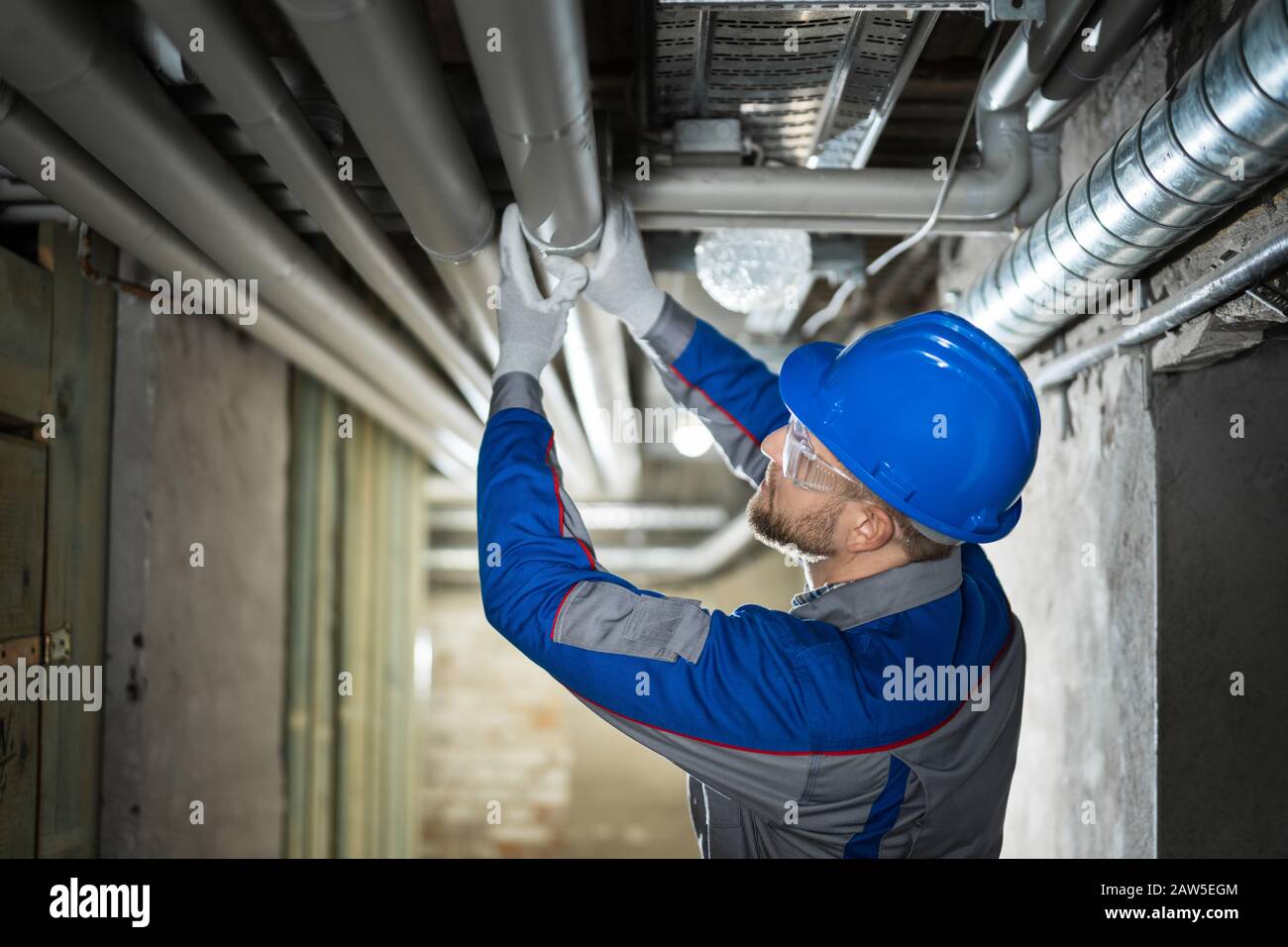 Male Worker Inspecting Water Pipes For Leaks In Basement Stock Photo ...