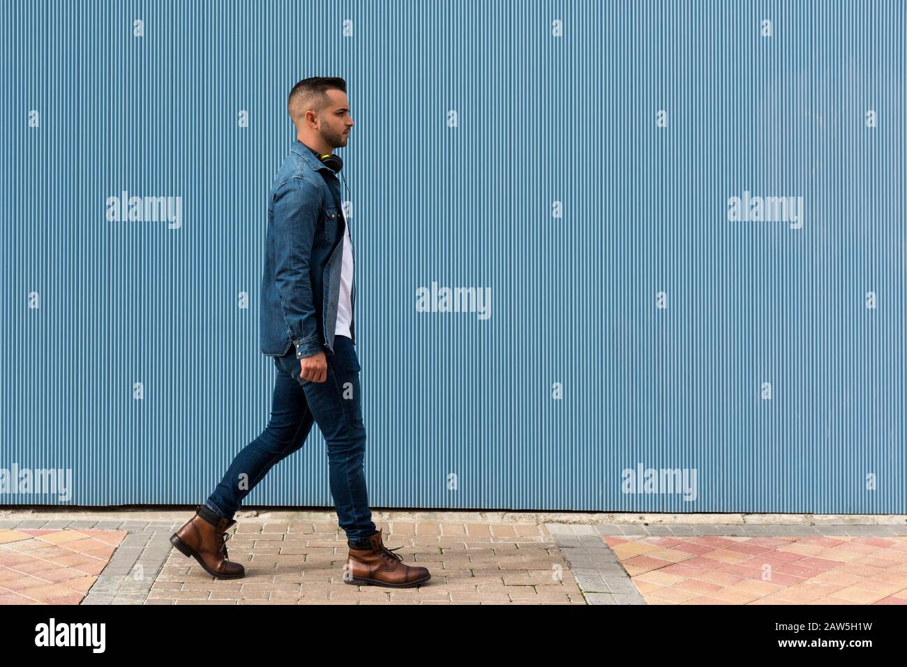 Portrait of a young man walking over blue background Stock Photo - Alamy