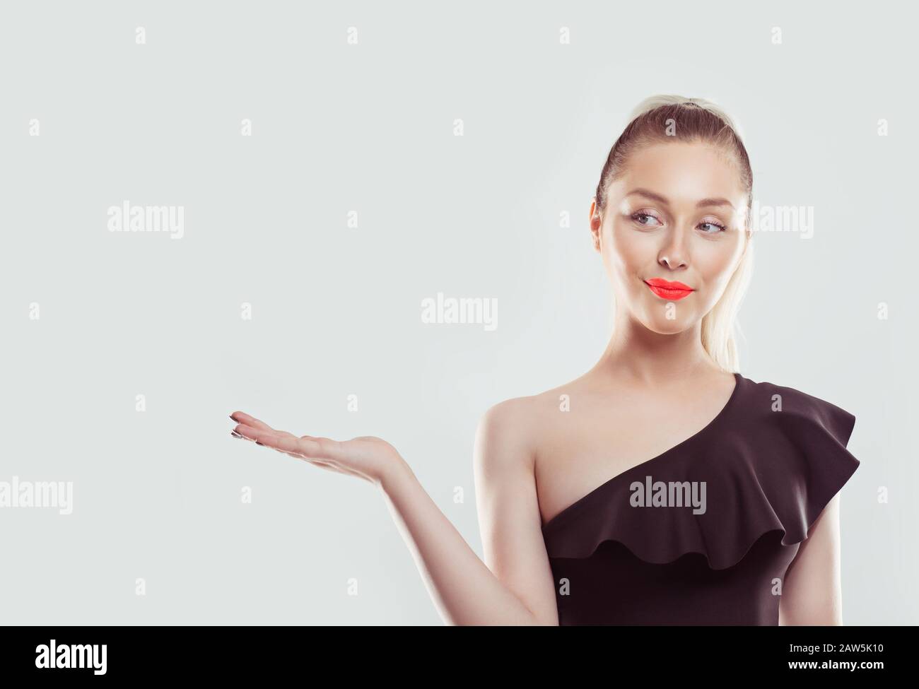 Look here. Happy smiling beautiful young woman shows a hand showing ...