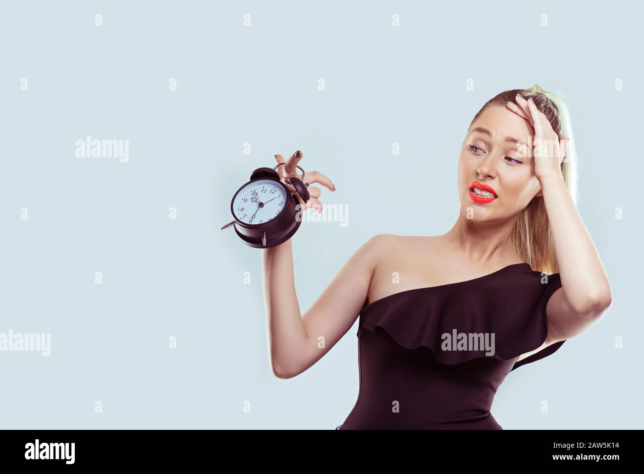 Anxious young woman looking at alarm clock. Time pressure concept ...