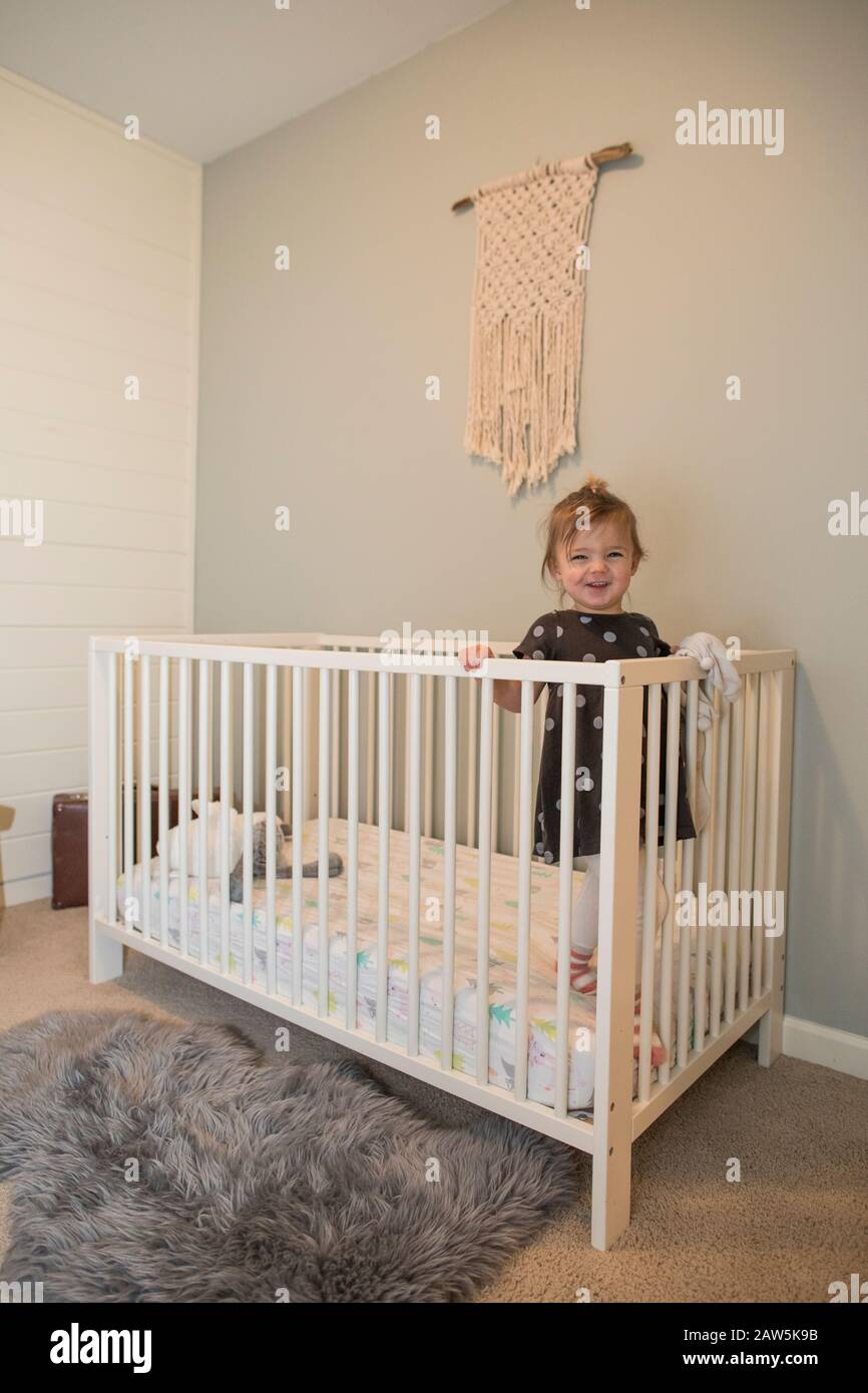 Portrait of cute toddler girl standing inside her crib Stock Photo - Alamy