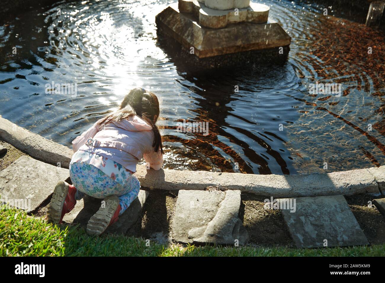 Girl playing with water in public park pond Stock Photo - Alamy