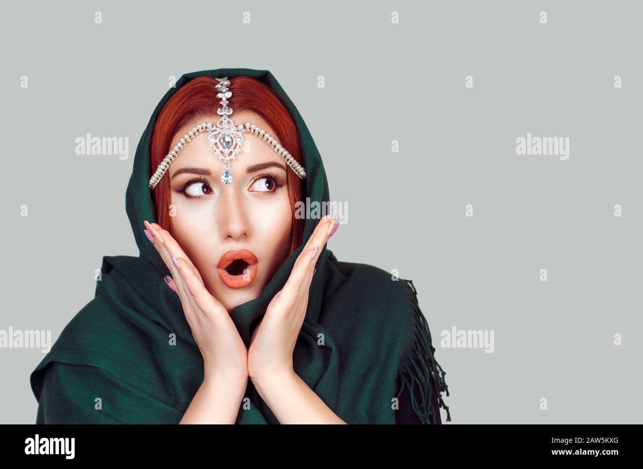 Shocked beautiful woman with big eyes, open month, with hand on cheeks ...