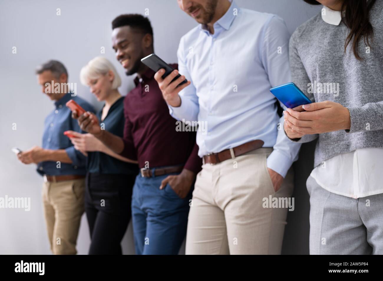 Row Of Diverse Businesspeople Using Phones In Office Stock Photo - Alamy