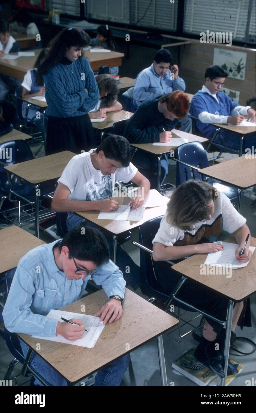 Male and female students sitting at desks take written test in biology ...