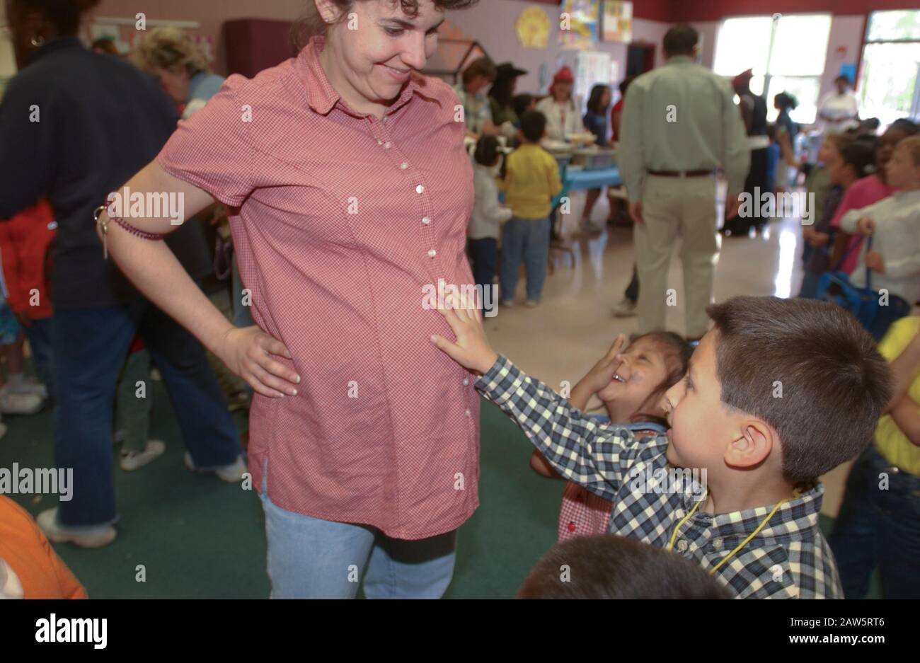 Kindergarten students feel the pregnant belly of their teacher while waiting in the lunch line ...