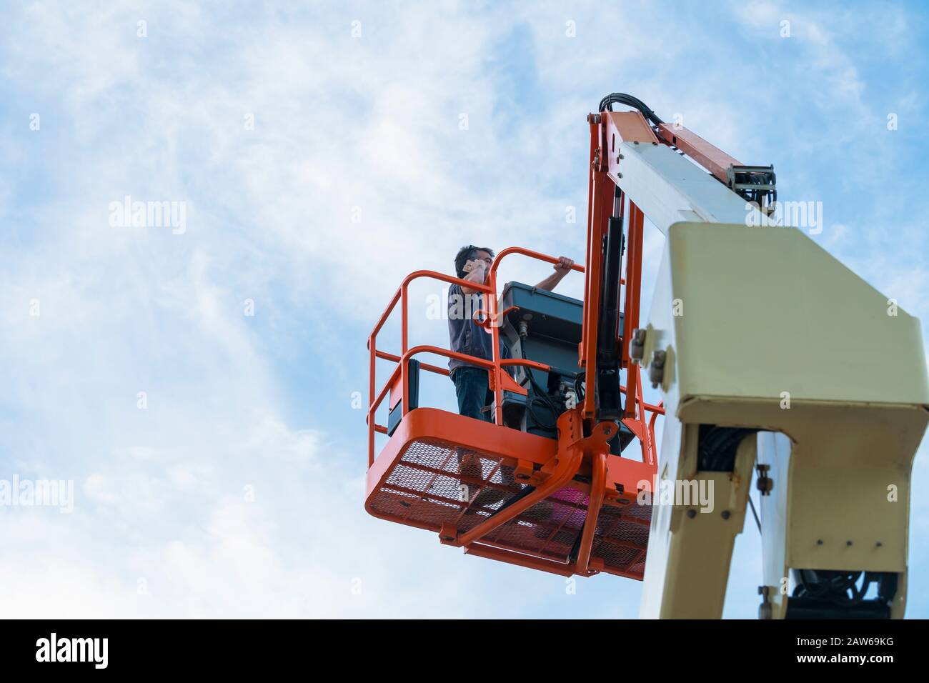 Worker using his phone on an elevated platform Stock Photo - Alamy