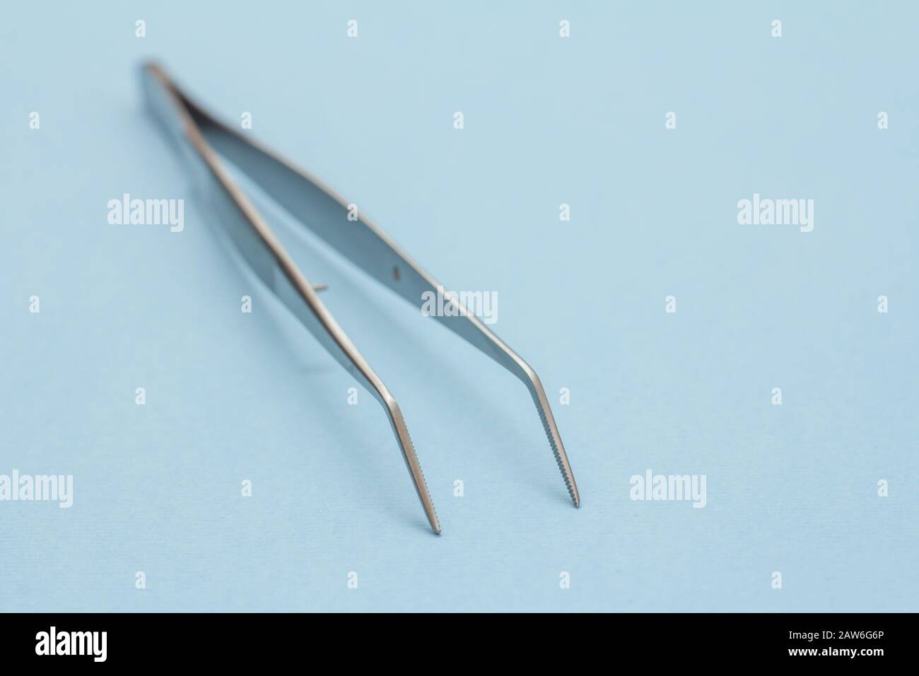 Close-up view of tweezers on blue background. Metal medical instruments ...