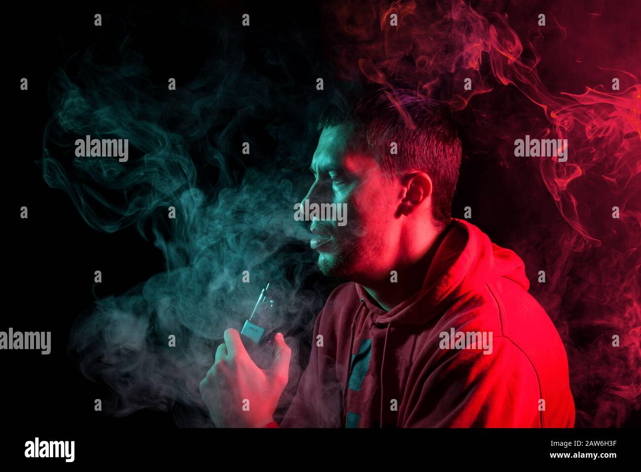The man smoke an electronic cigarette on the dark background. Young man ...